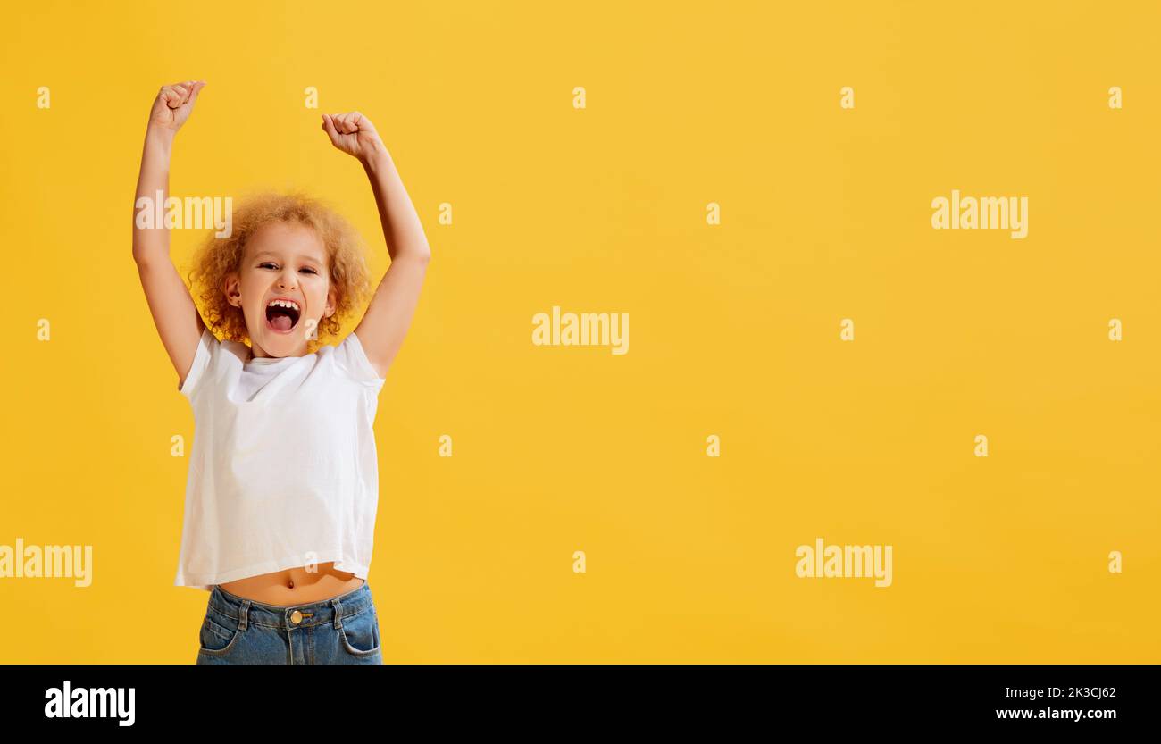 Thrilled little girl, kid shouting in rejoice and raising hands up ...