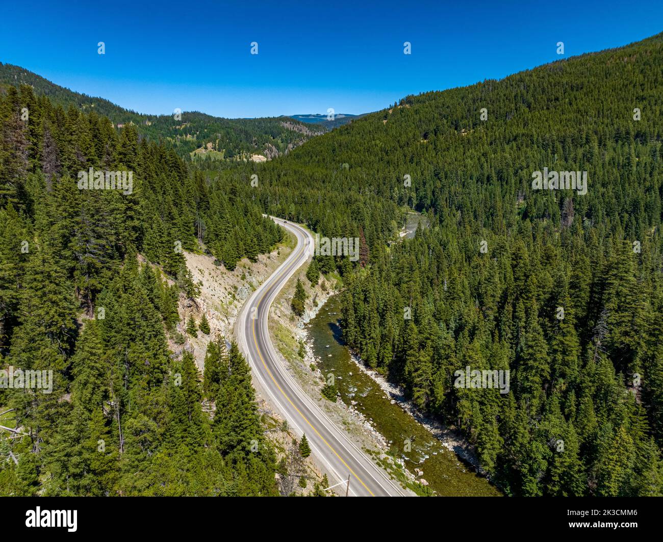 Drone view of Crowsnest Highway by river passing through rocks, dense ...