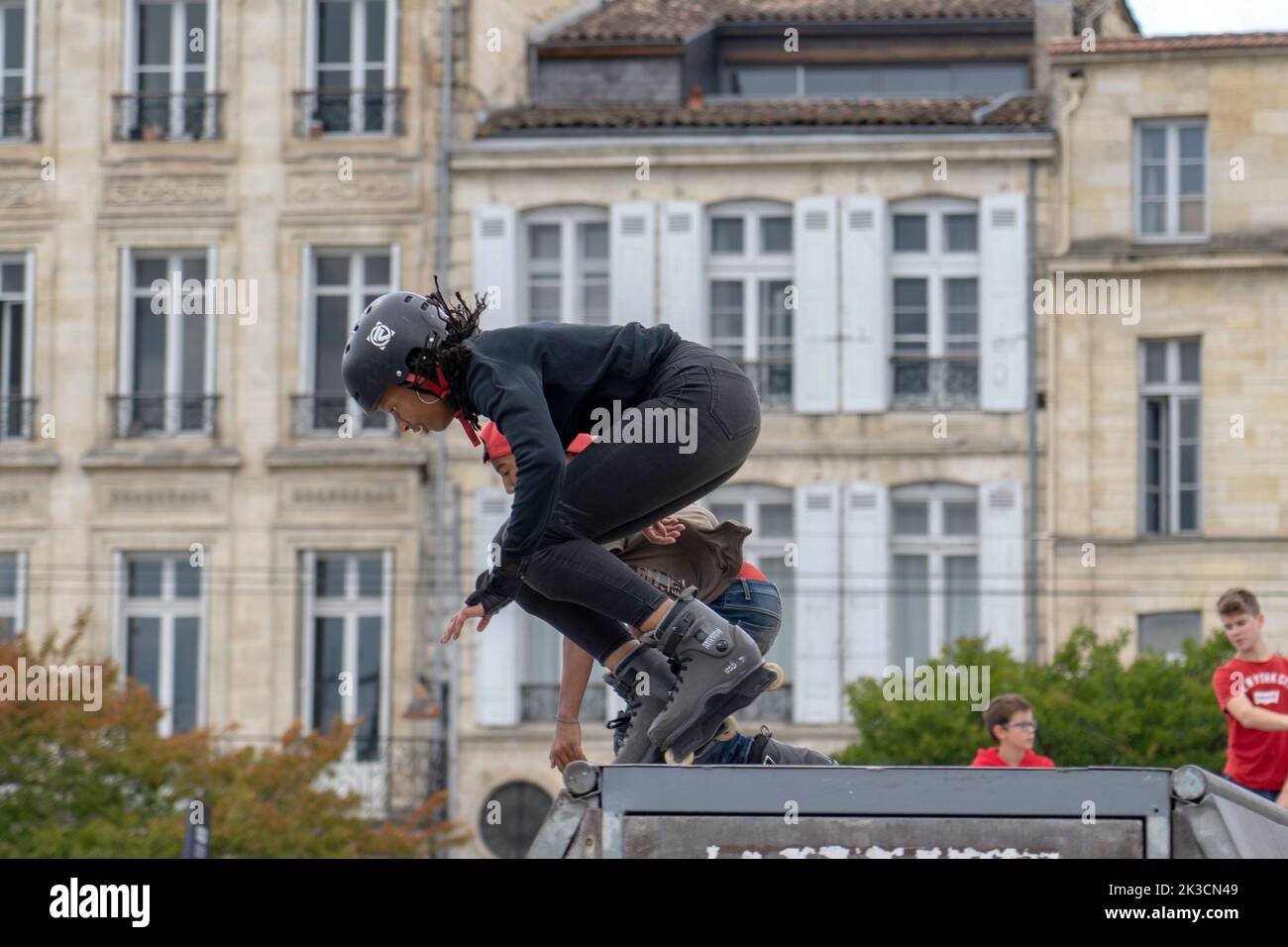 An inline rollerblader performing jumps at a local skate park in ...