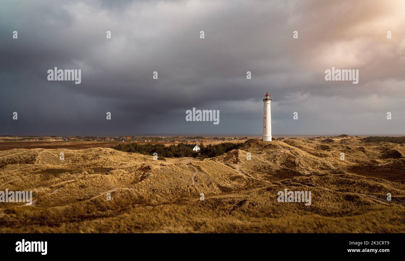 A landscape shot of the Lyngvig Lighthouse in the hills under a cloudy ...