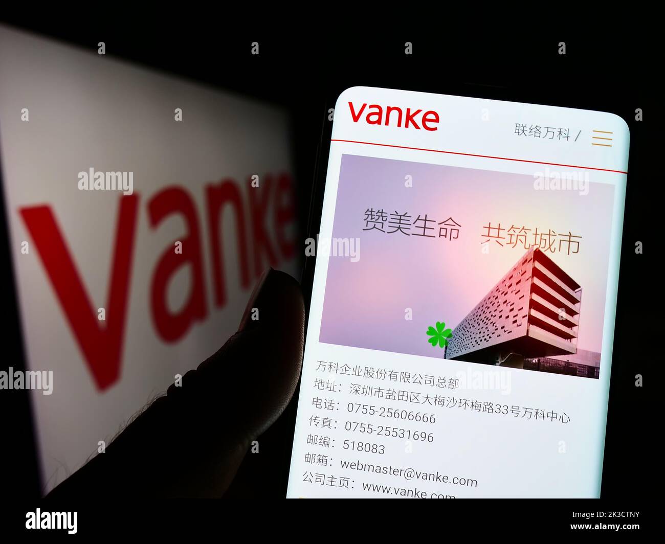 Person holding smartphone with webpage of Chinese real estate company ...