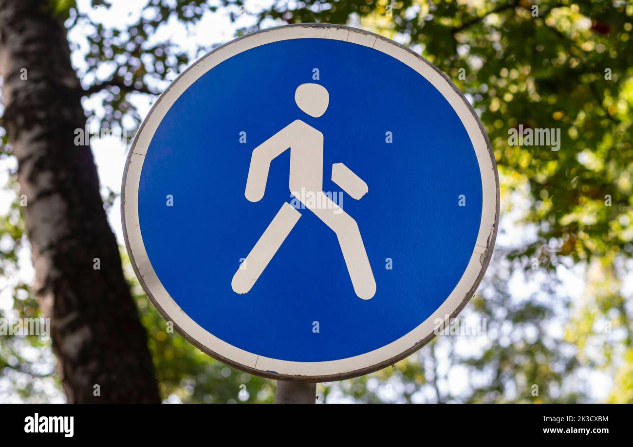 Round blue road sign with white human icon, selective focus with copy ...