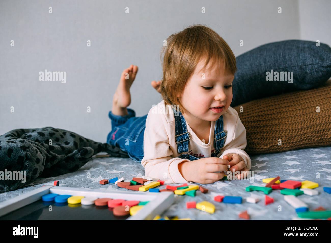 Child plays at home an educational game with a multi-colored magnetic ...