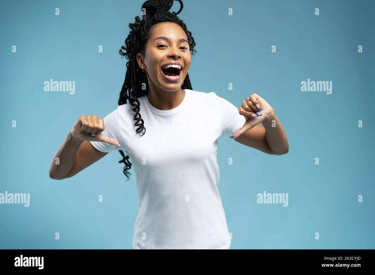 Smiling African American woman wearing white t-shirt pointing finger at ...