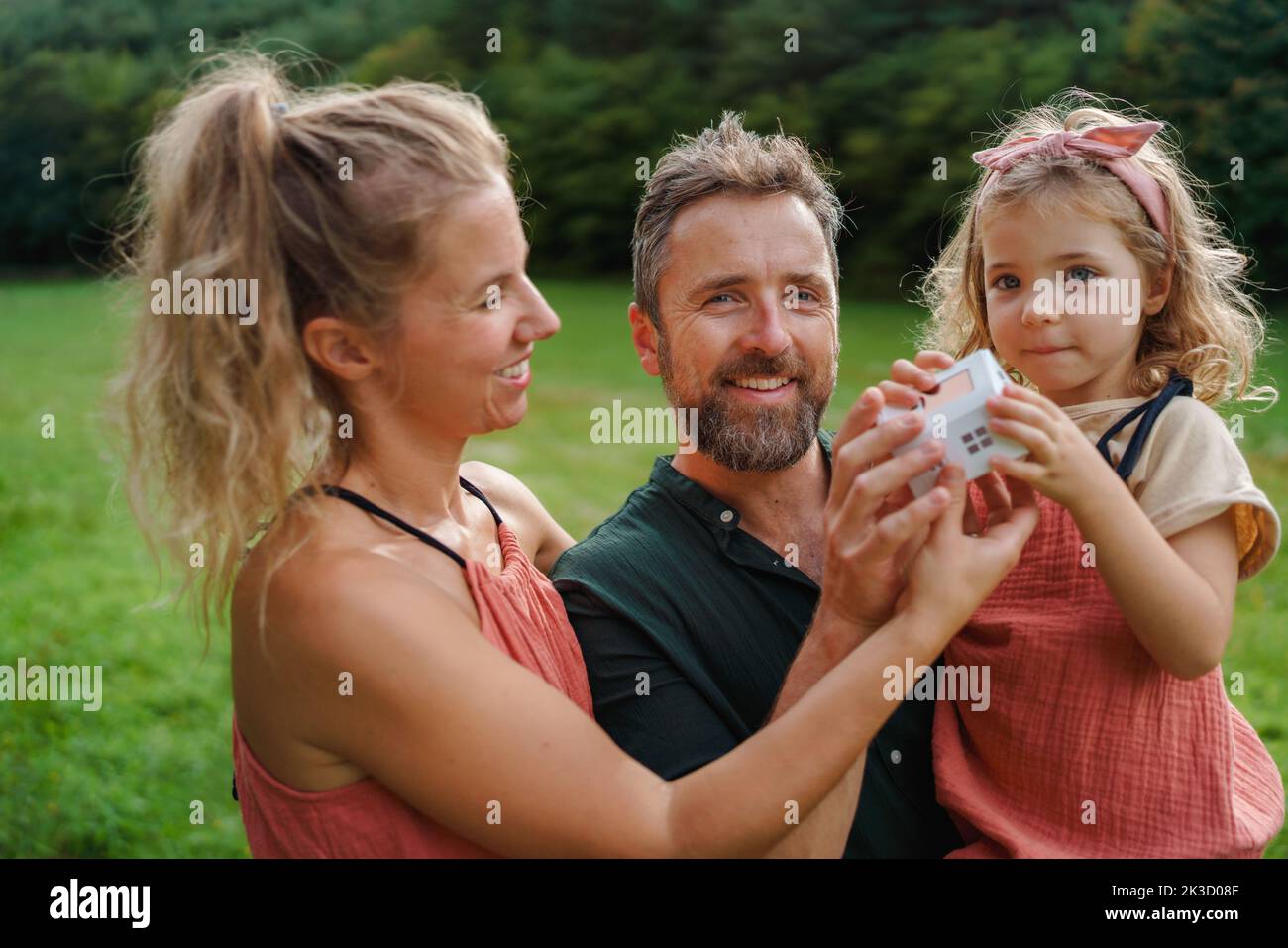 Little girl with her parents holding paper model of house with solar ...