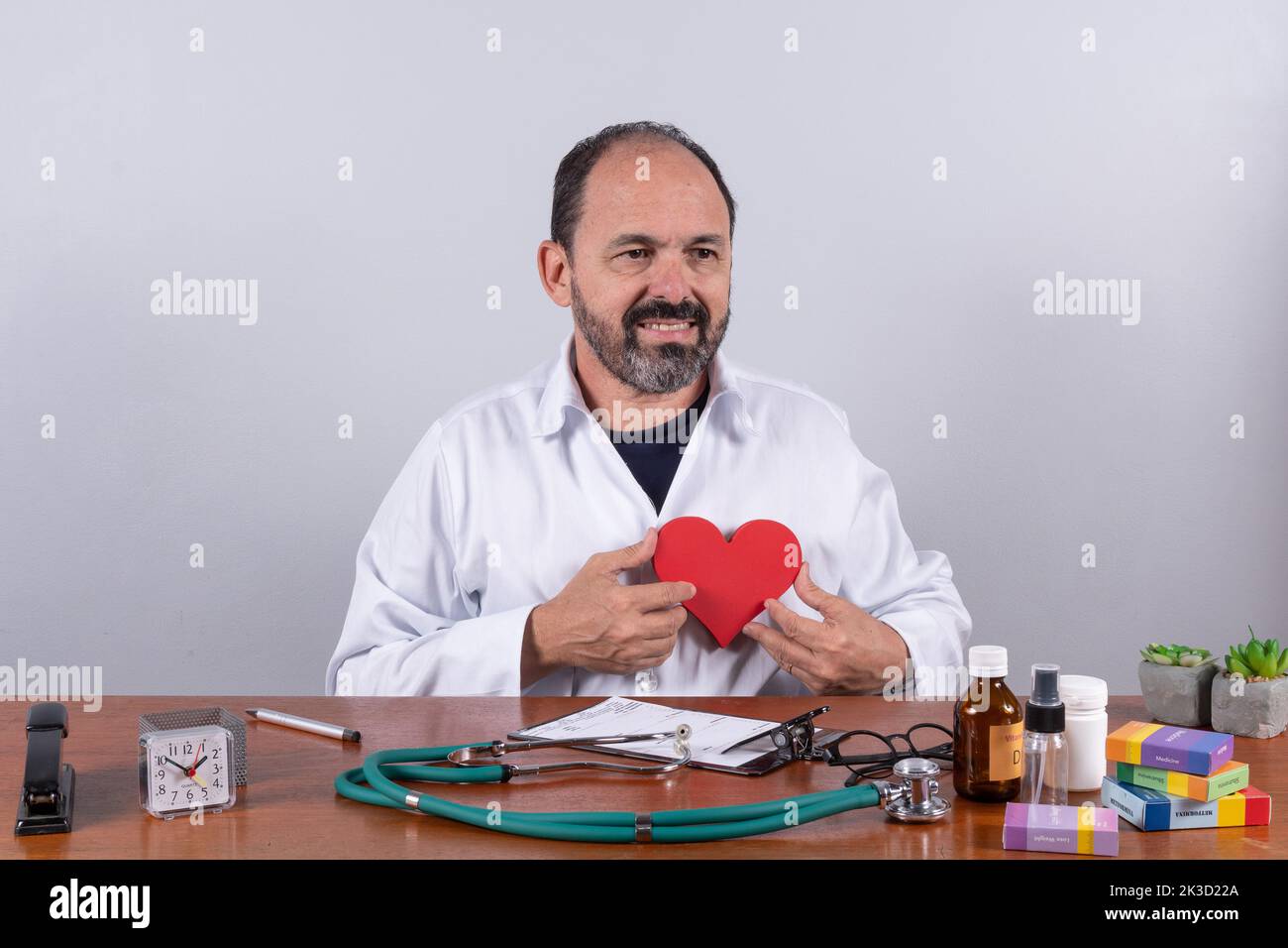 Portrait of senior mature doctor holding a heart shape and looking at ...