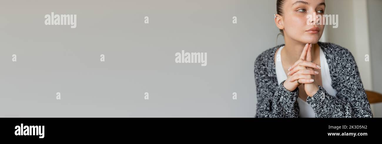 Woman in knitted cardigan looking away near wall at home, banner,stock ...