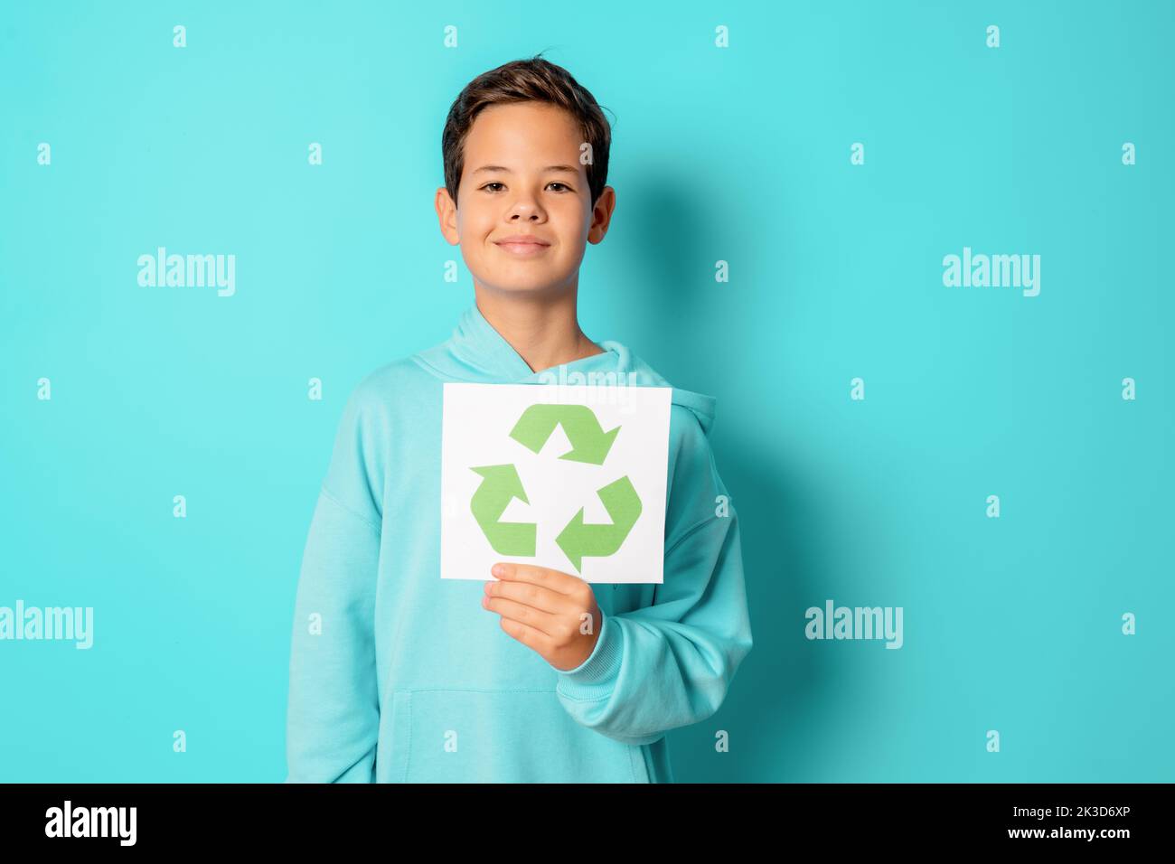 Child boy holding recycling symbol paper standing isolated over green ...