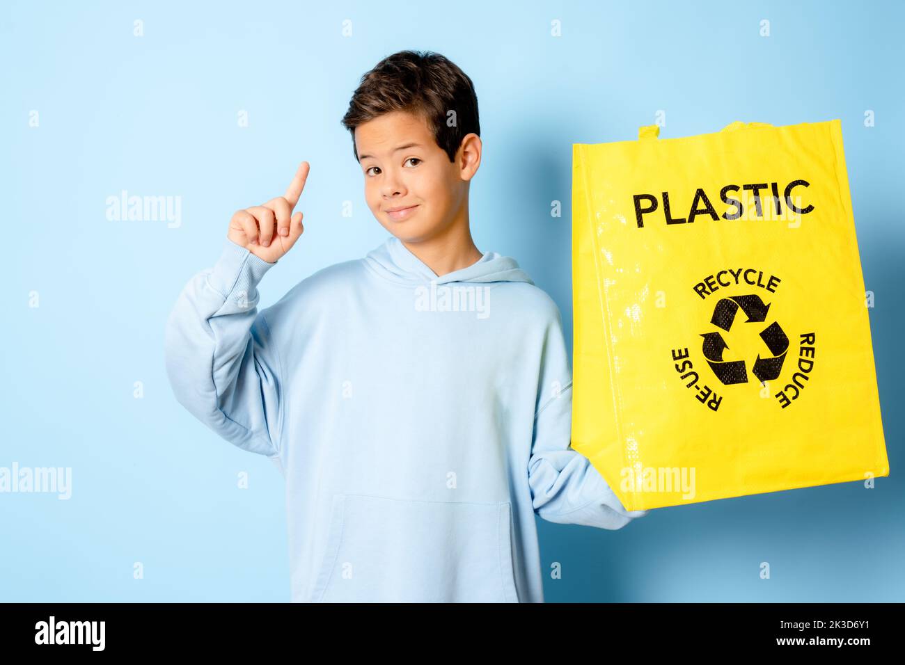 Child boy holding recycling plastic bag standing isolated over blue ...