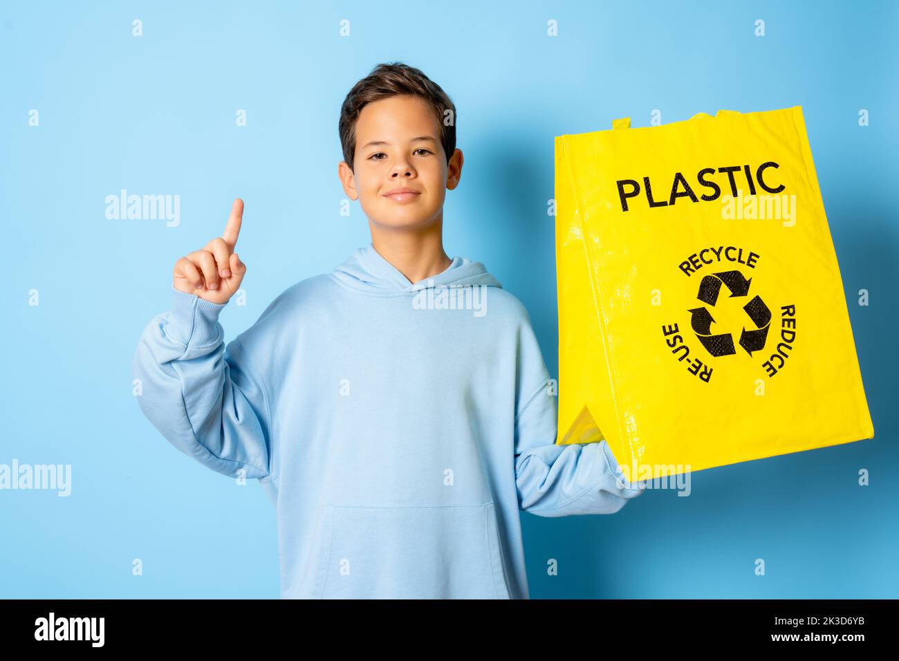 Child boy holding recycling plastic bag standing isolated over blue ...