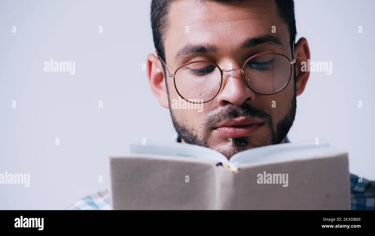 focused student in eyeglasses reading blurred book isolated on grey ...