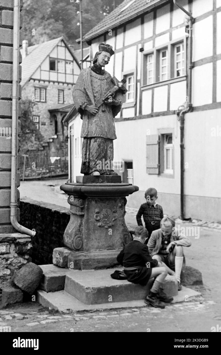 Jungen spielen zu Fuß der Johannes von Nepomuk-Skulptur in Blankenheim ...