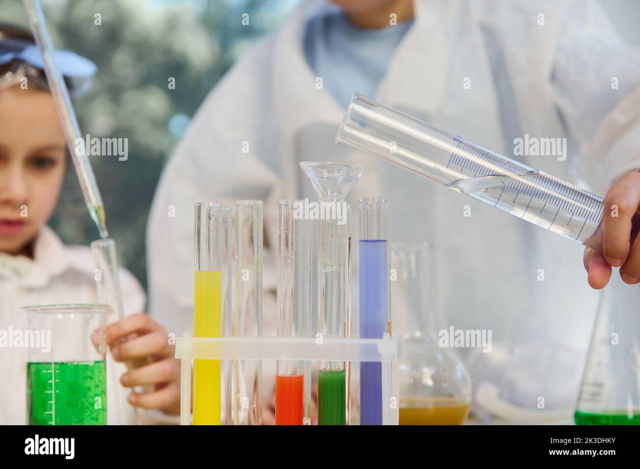 Focus on measuring cylinder in schoolchild hand, pouring water into ...