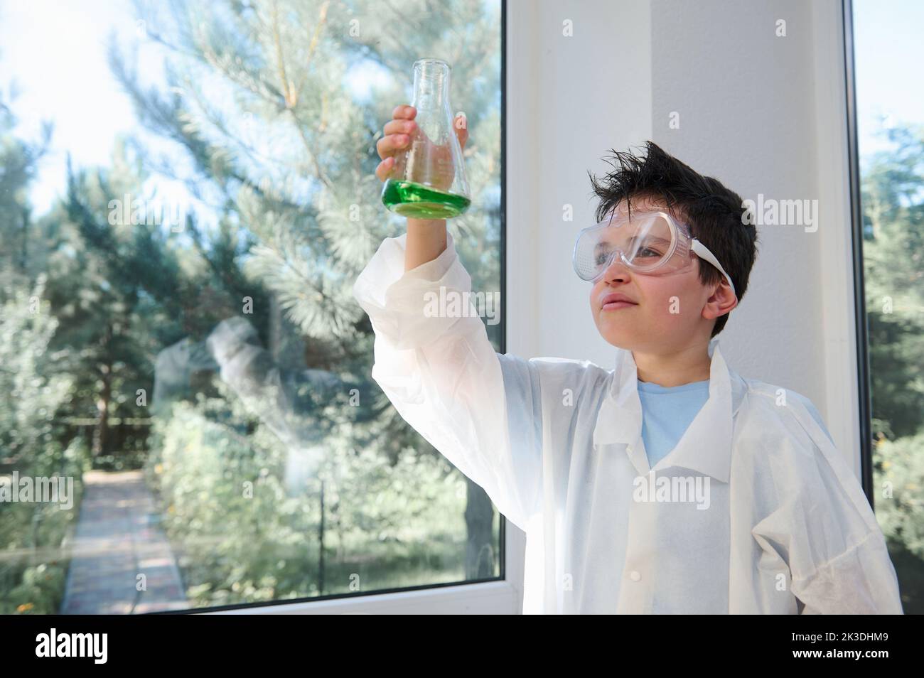 Adorable dark-haired child boy wearing safety goggles and lab coat ...