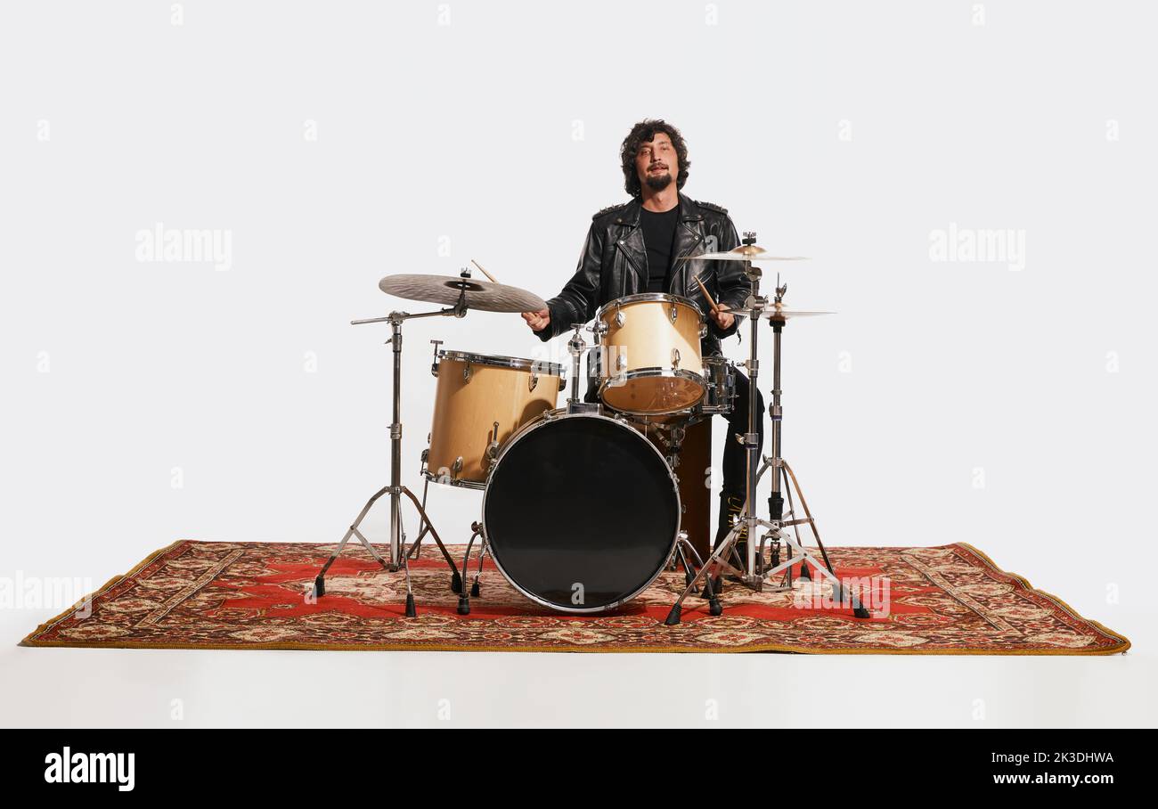 Studio shot of young musician with drums performing over white ...