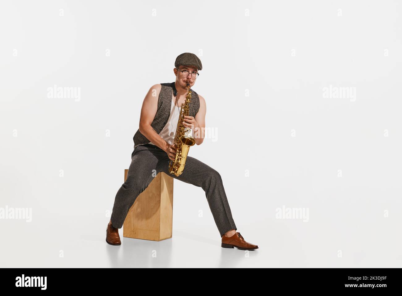 Young musician in retro style outfit playing saxophone isolated over ...