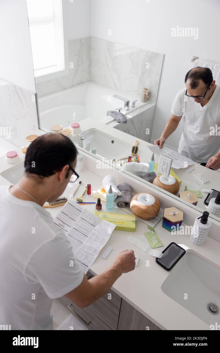Man reading instructions for Covid rapid antigen test in bathroom Stock ...