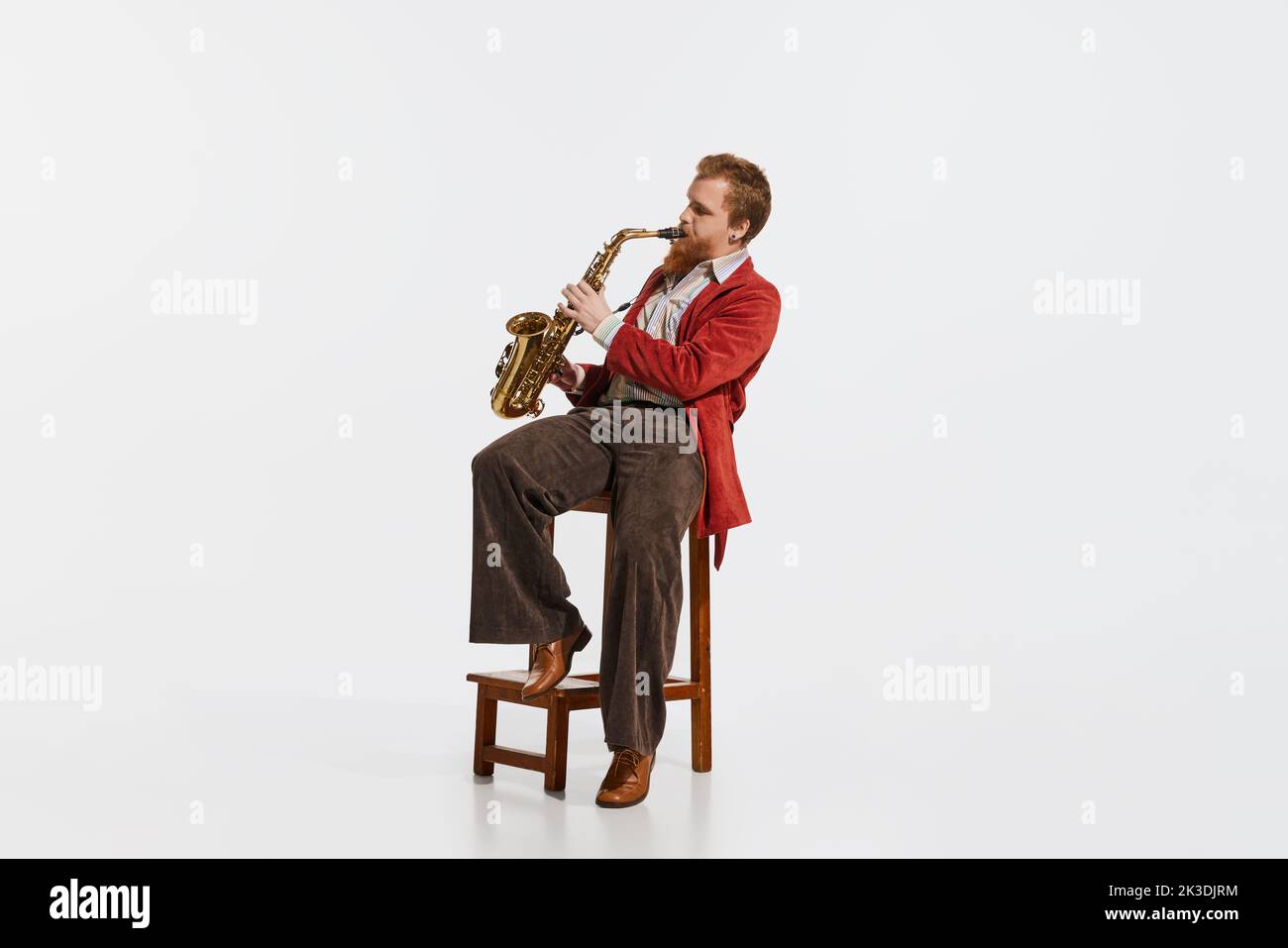 Young musician in retro style outfit playing saxophone isolated over ...