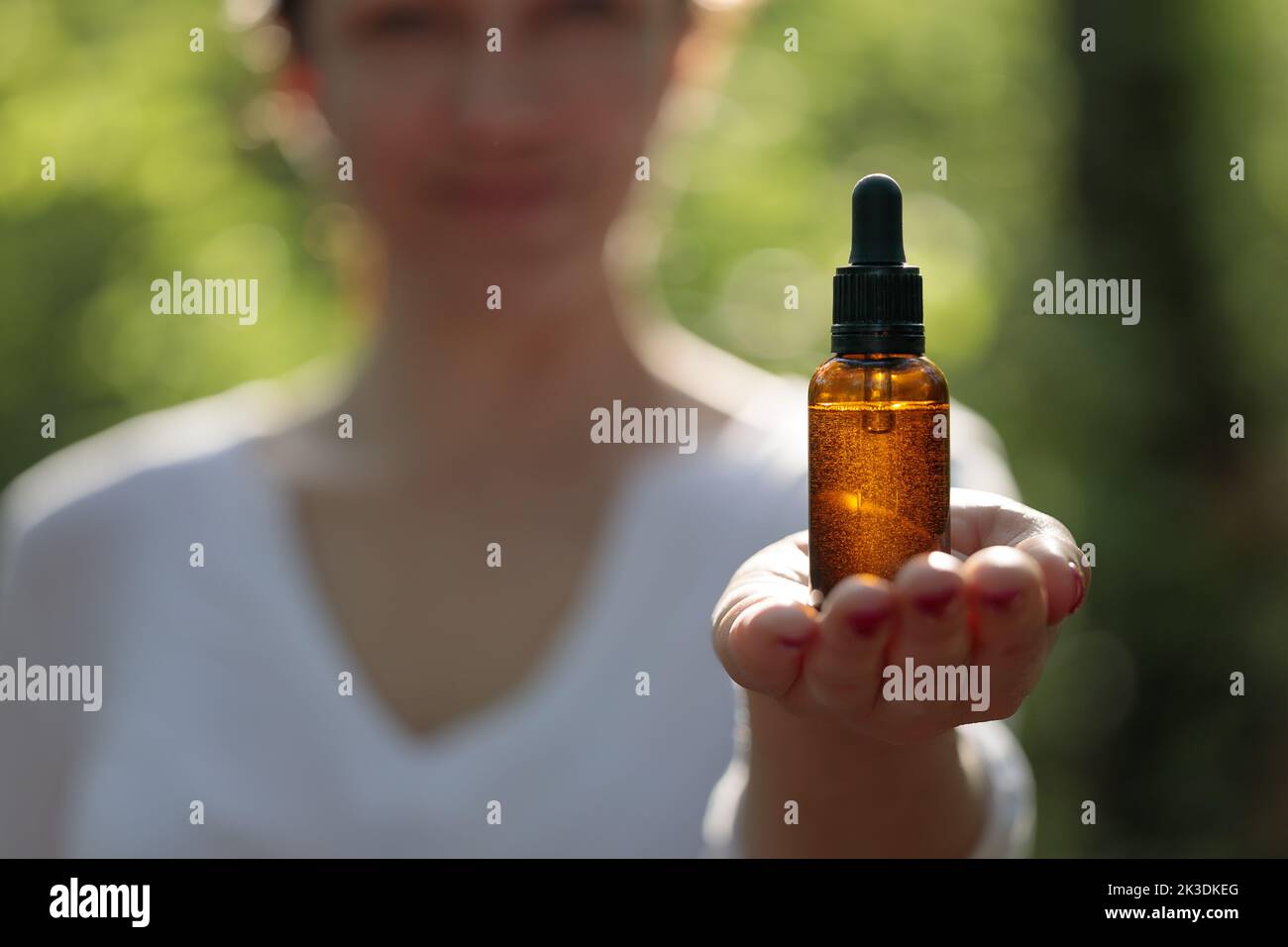 Woman hand holding essential oil, amber, cosmetic bottle Stock Photo ...