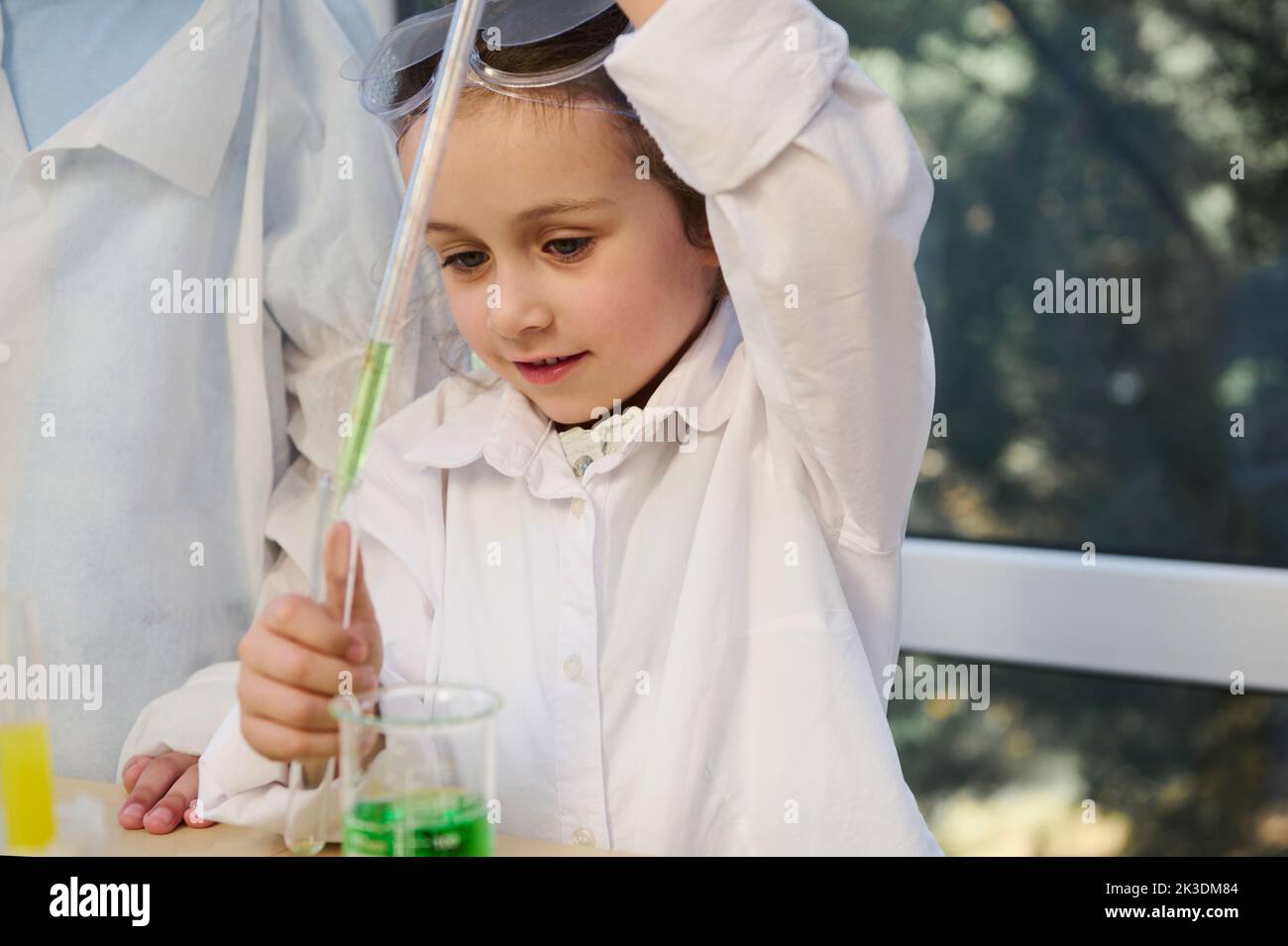 Smart Caucasian schoolgirl, elementary age student wearing white lab ...