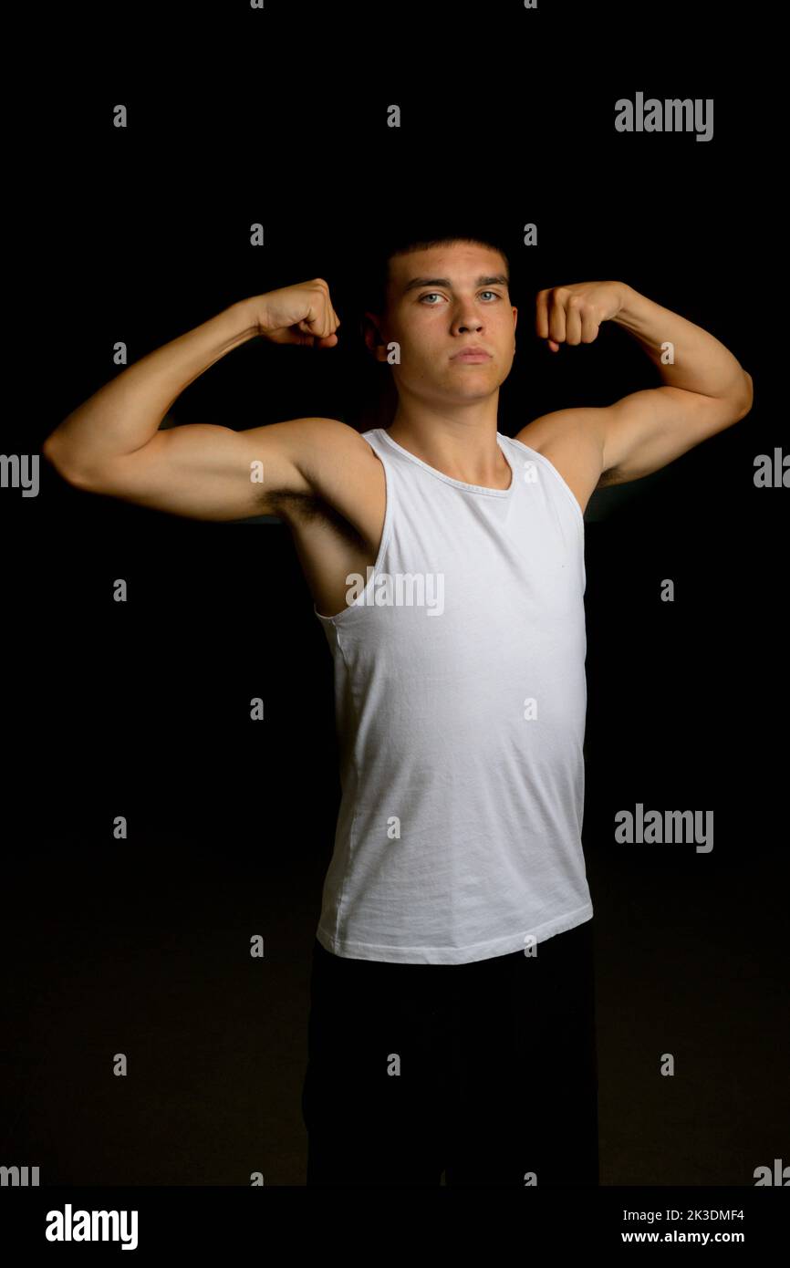 19 year old teenage boy wearing a tank top flexing his arm muscles ...
