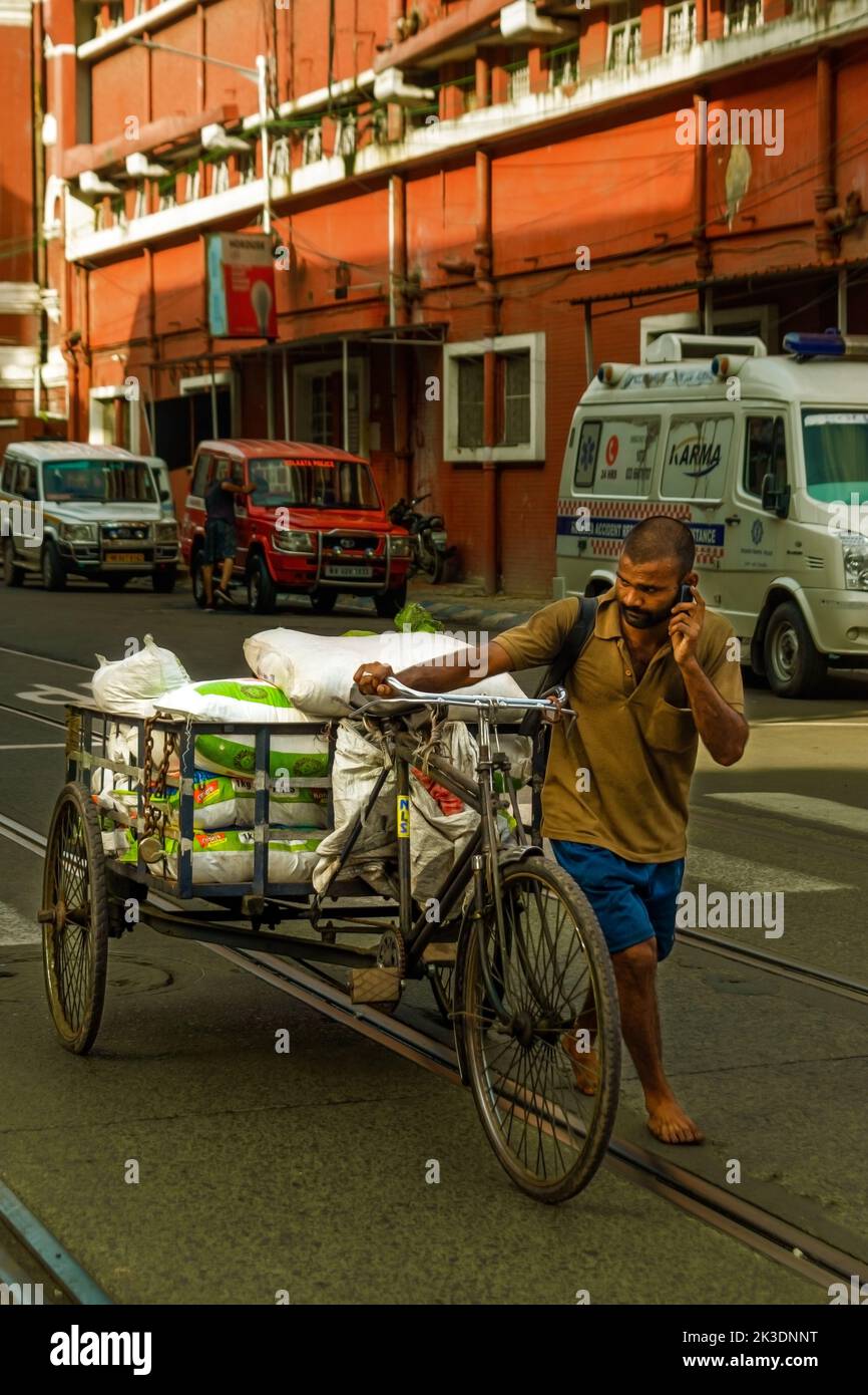 A vertical closeup of a commuter carrying goods on a tricycle rickshaw ...