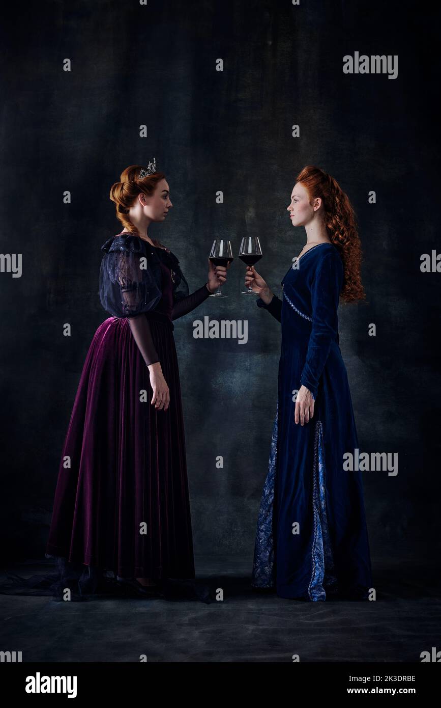 Portrait of two beautiful women in image of queens standing face to ...