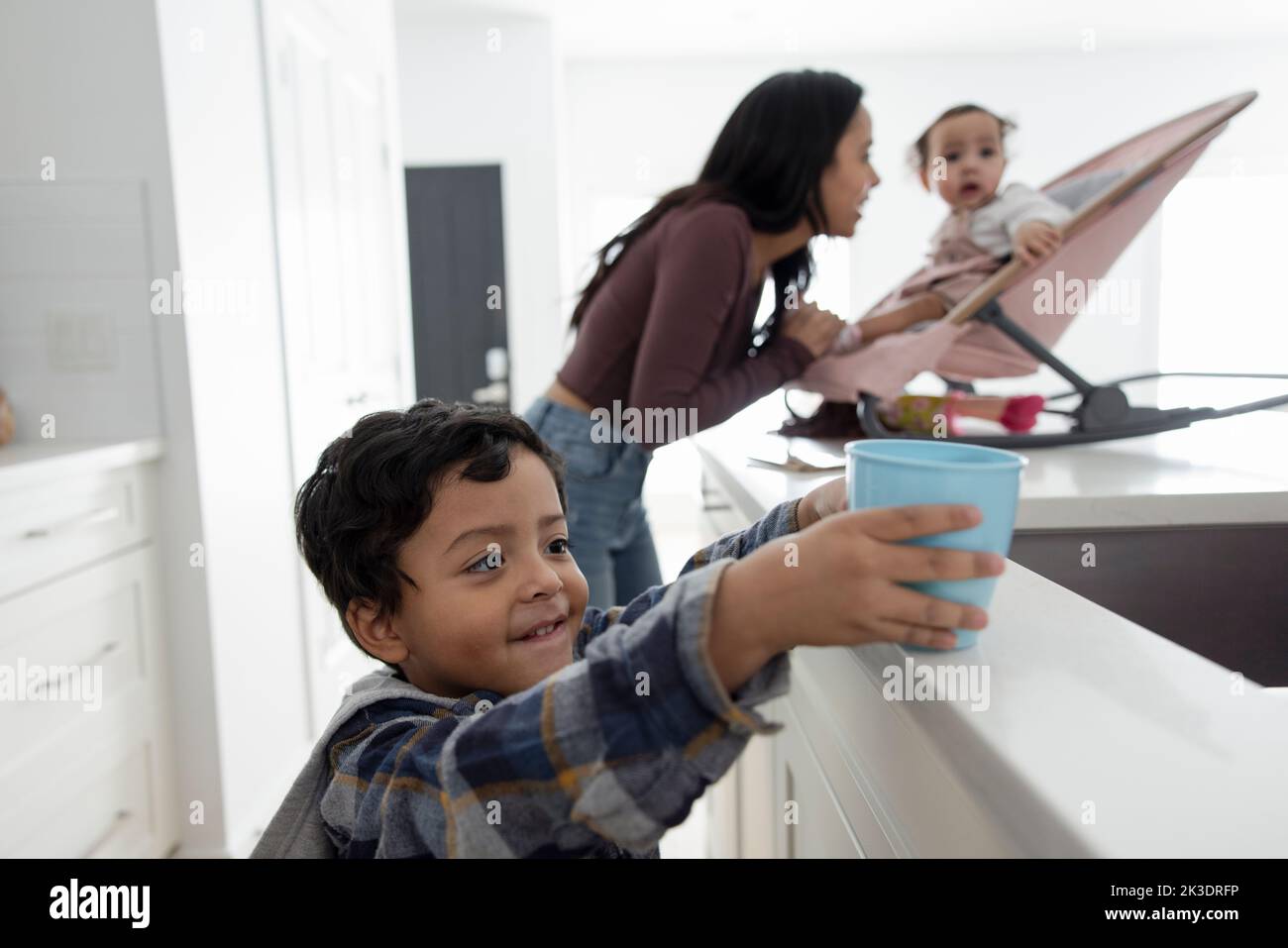 Boy reaching for cup on kitchen counter Stock Photo - Alamy