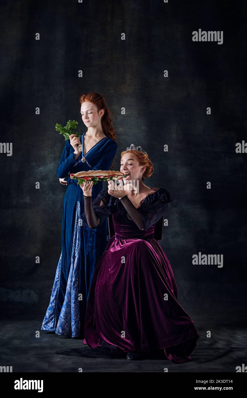 Portrait of two beautiful women, queen eating sandwich, princess eating ...