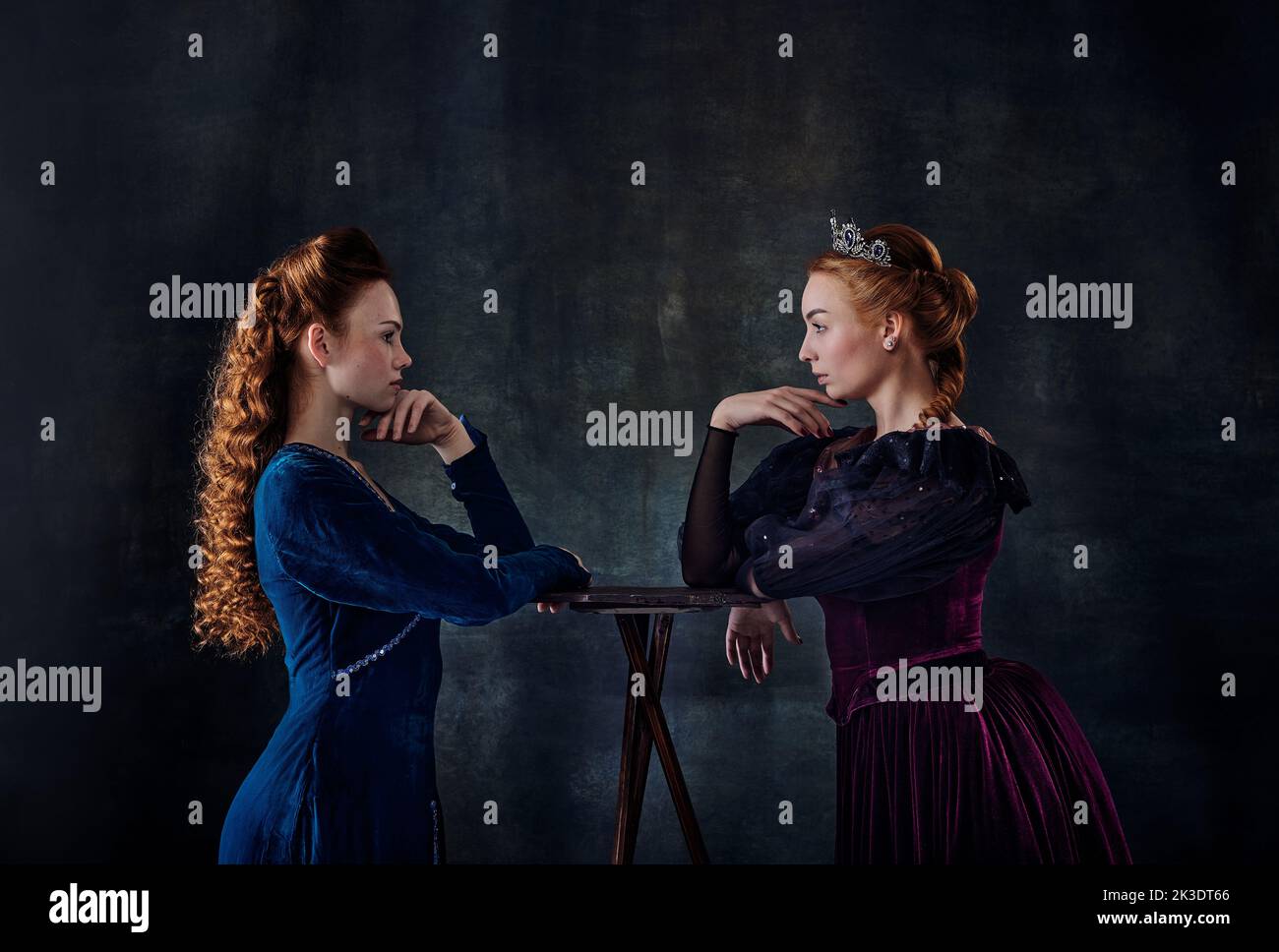 Portrait of two beautiful women in image of queens isolated over dark ...
