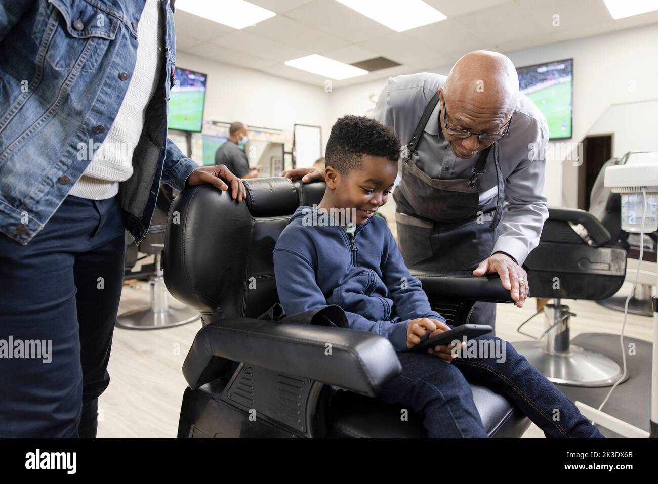 Boy customer showing smart phone to barber in barber shop chair Stock ...