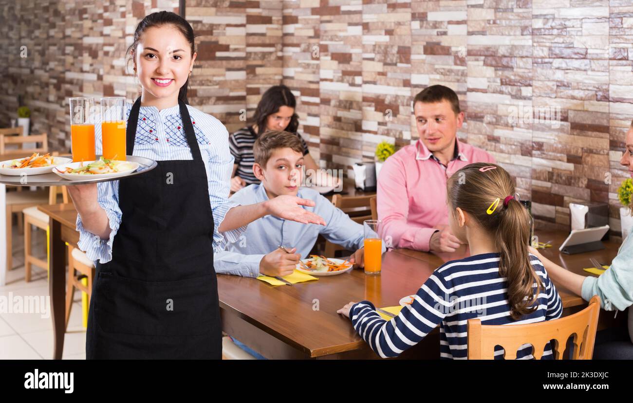 cheerful young waitress warmly welcoming guests to family cafe Stock ...