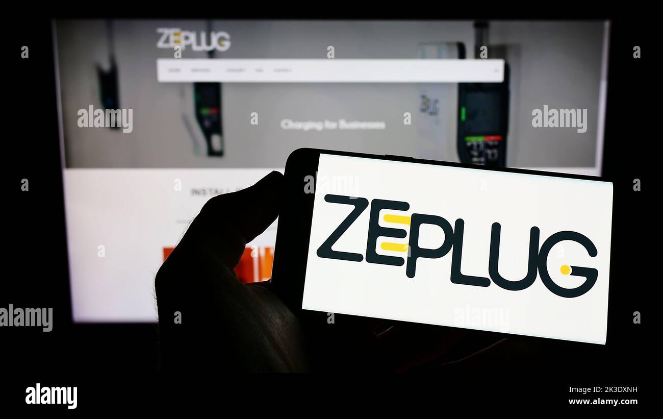 Person holding cellphone with logo of French EV charging company Zeplug ...