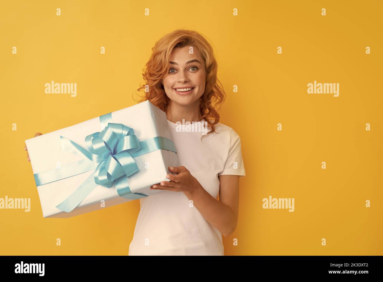 smiling redhead woman with present box on yellow background. happy ...
