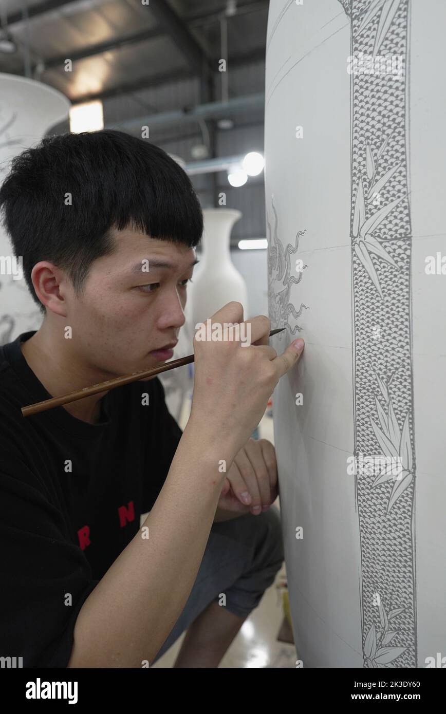 Vietnam, close to Hanoi, Ceramist painting a vase in a ceramic factory ...