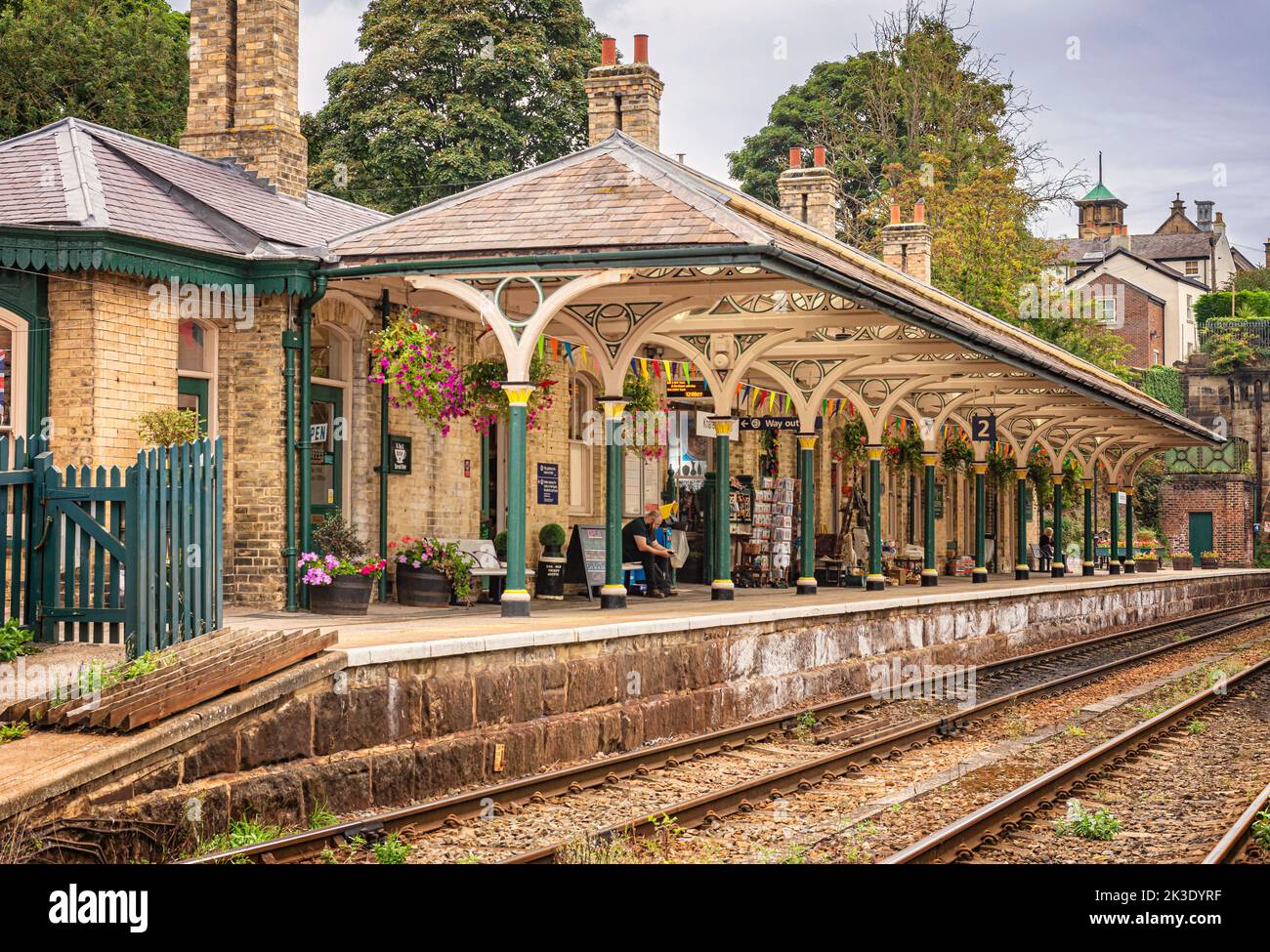Colourful flower baskets hang from an historic canopy with green ...