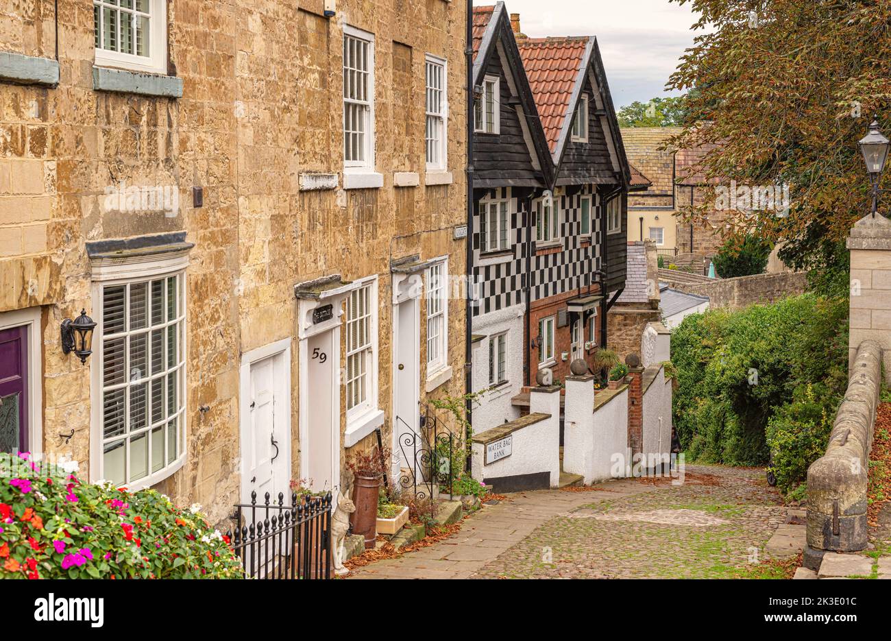Old cottages line a cobbled lane on a steep slope. One house has a ...