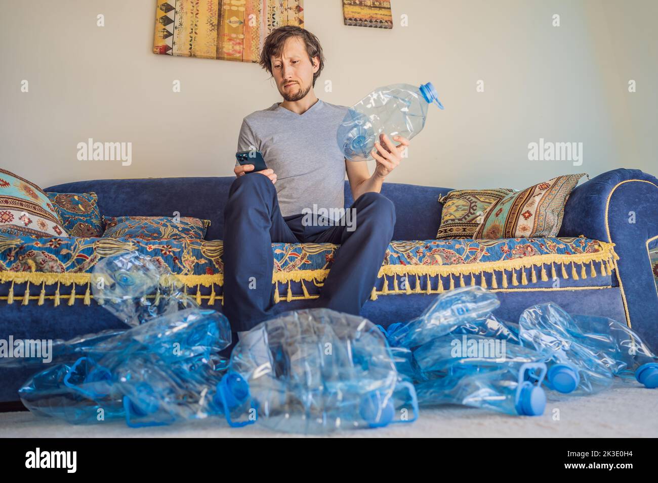 Young caucasian man hamong empty plastic bottles to recycle with sad ...