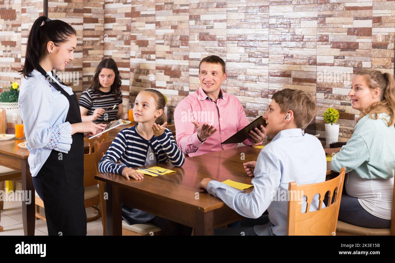 Happy hospitable waitress helping visitors Stock Photo - Alamy