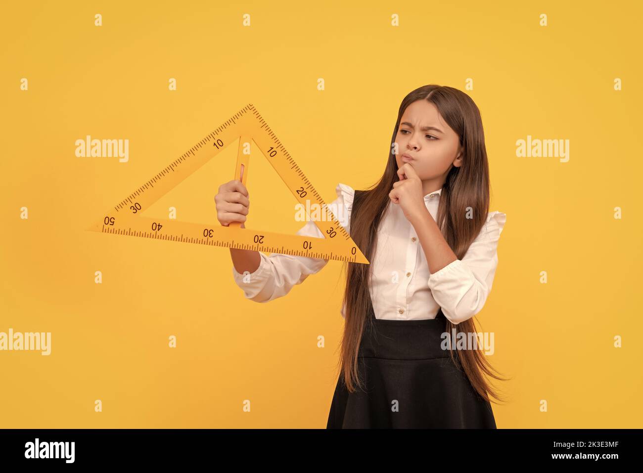 pondering child in school uniform hold mathematics triangle for ...