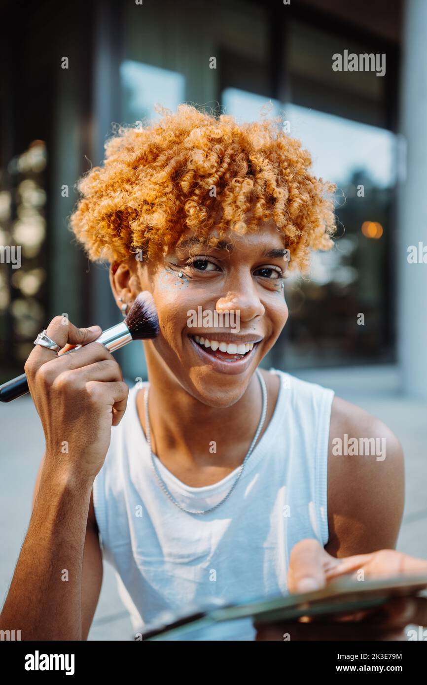 Positive multiracial charismatic boy preparing makeup at his face with ...