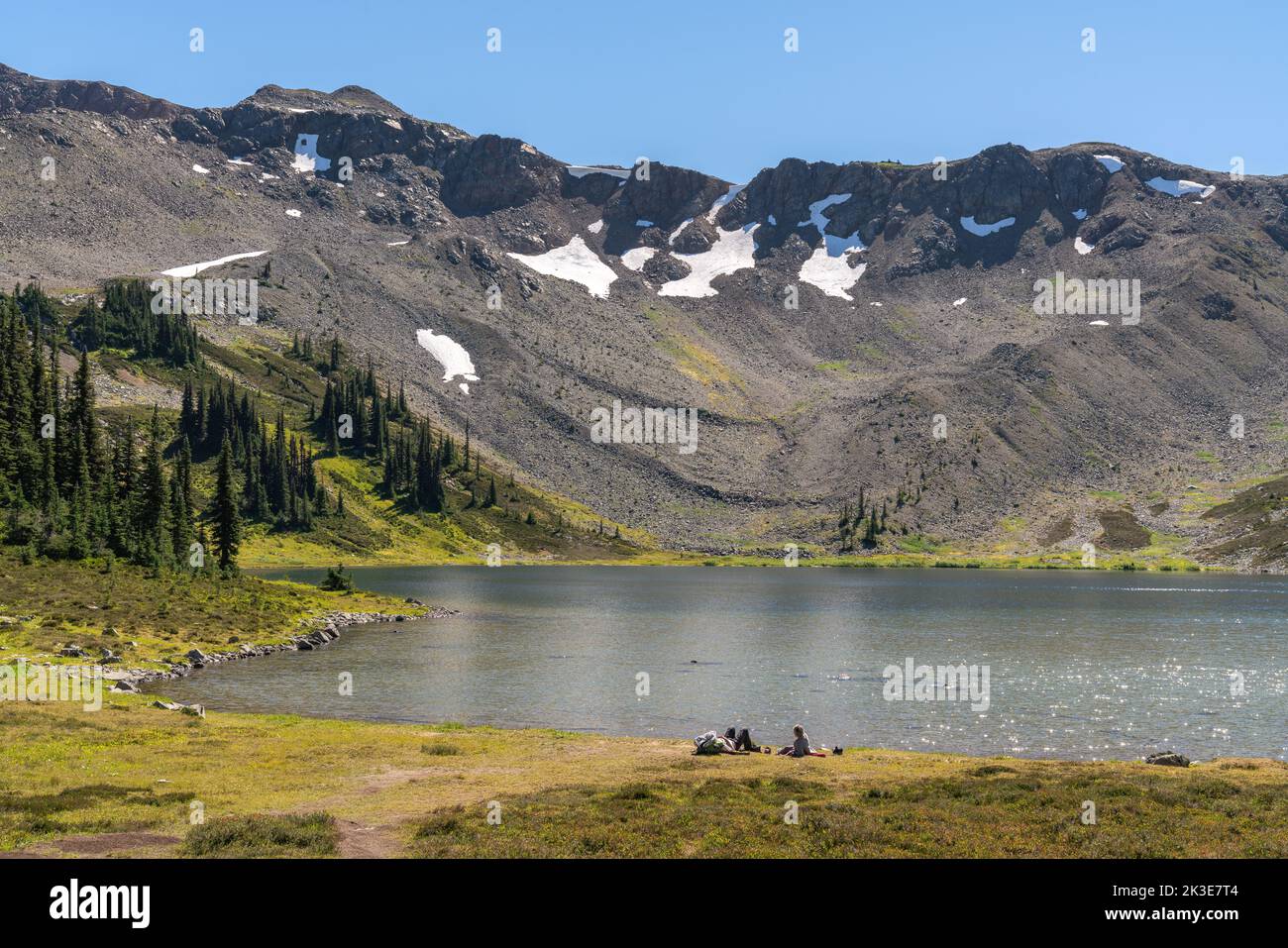 Hikers enjoy a serene alpine lake along the Panorama Ridge Trail in BC ...