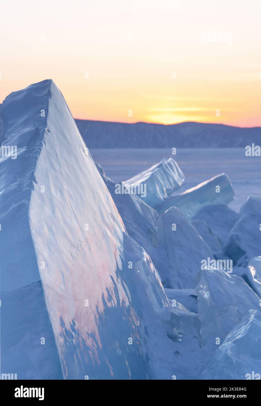 Winter landscape with ice hummocks glittering in the sun and mountains ...