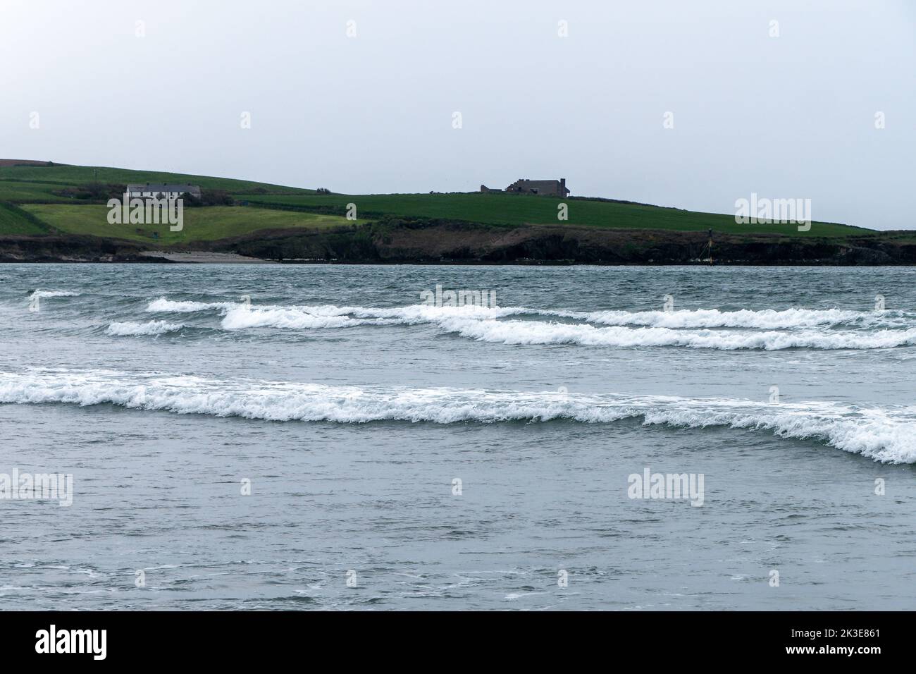 Sea at high tide. A building on a hill, seashore. Gray gloomy sky ...