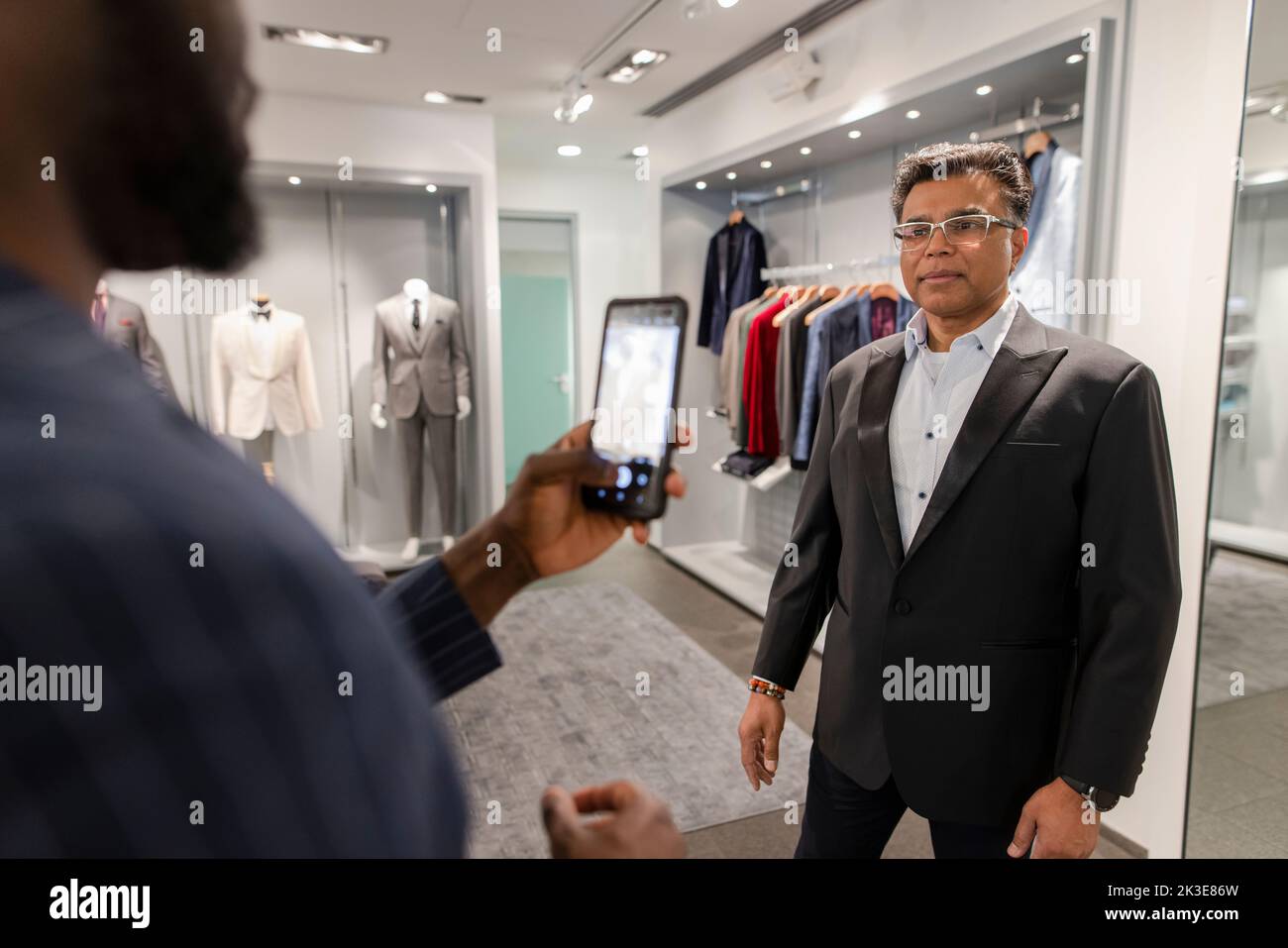 Male tailor fitting a man with a suit over white background Stock Photo ...