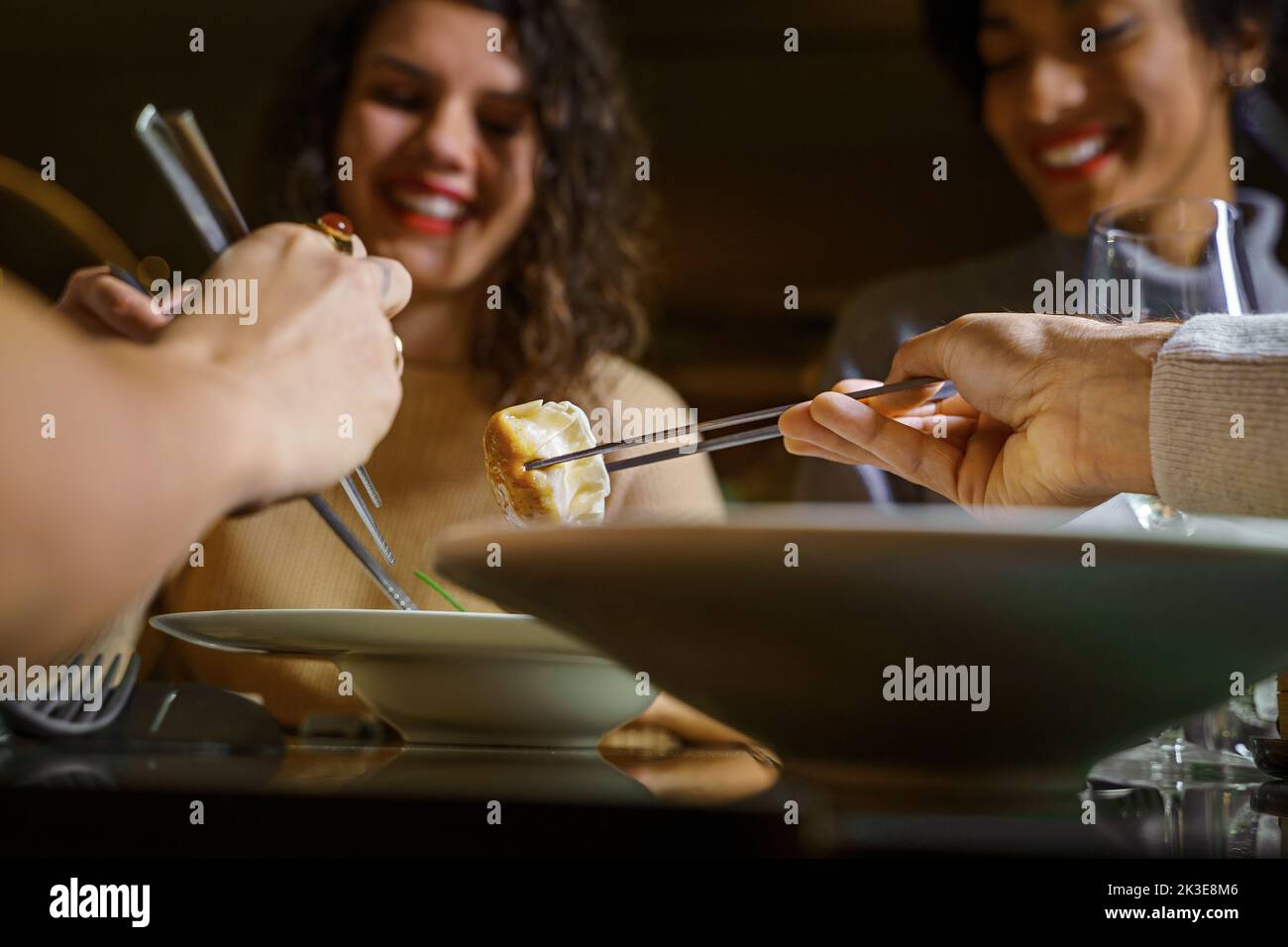 Multiethnic group of smiling young friends eating dim sum dumplings at ...