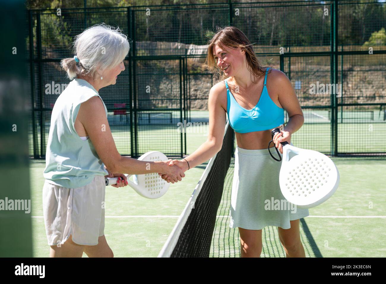 Senior and young women handshaking after padel tennis match Stock Photo ...