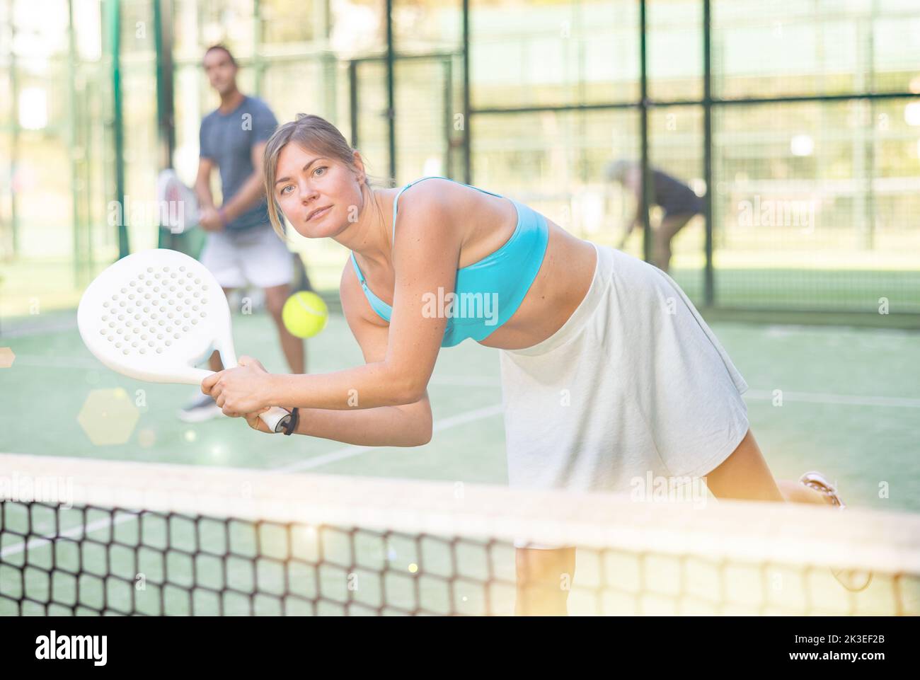 Young woman performing two-handed forehand during paddleball match on ...