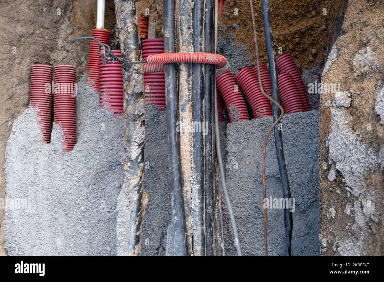 Network cables in red corrugated pipe are buried underground on the ...