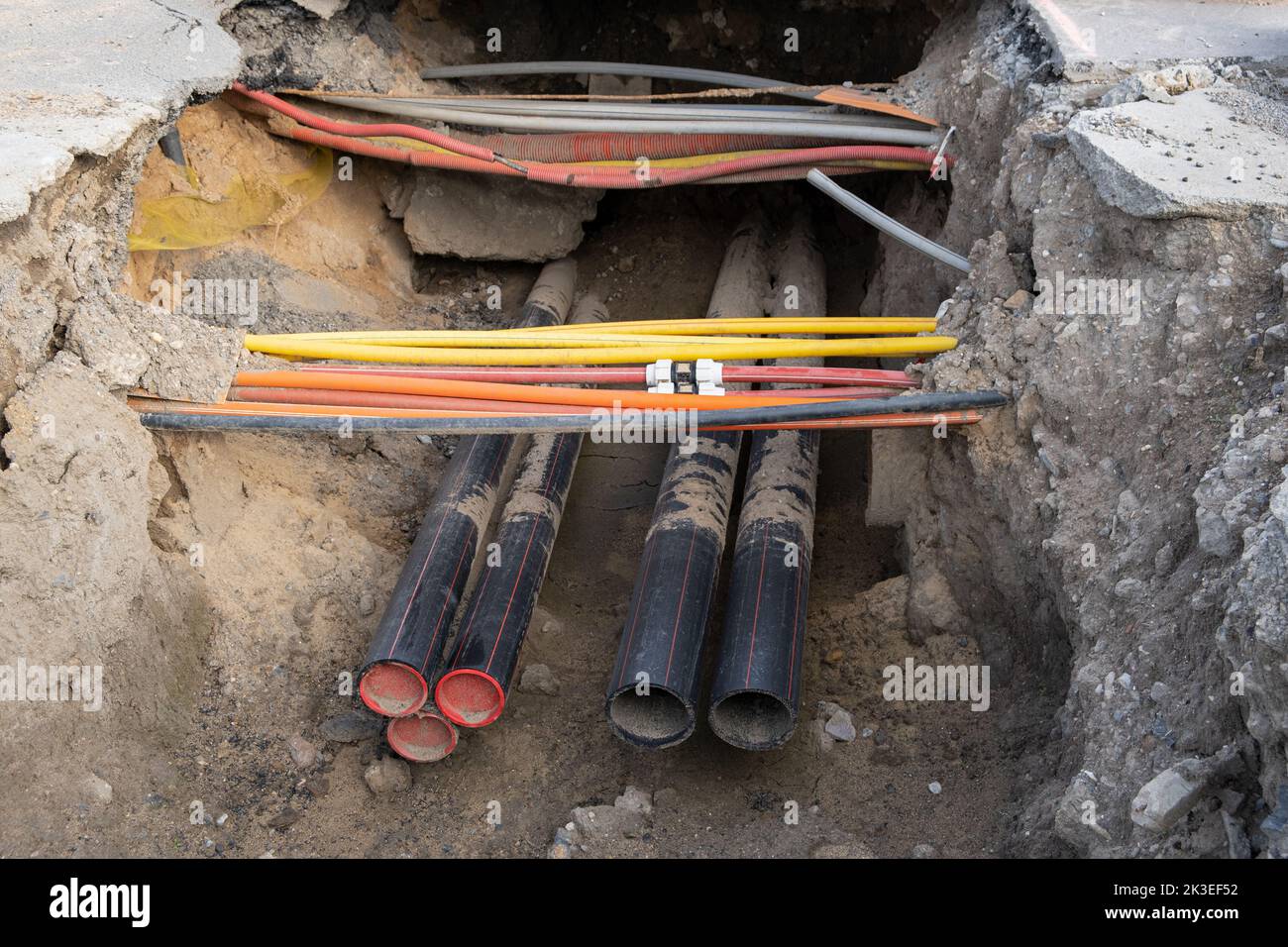 Network cables in red corrugated pipe are buried underground on the ...